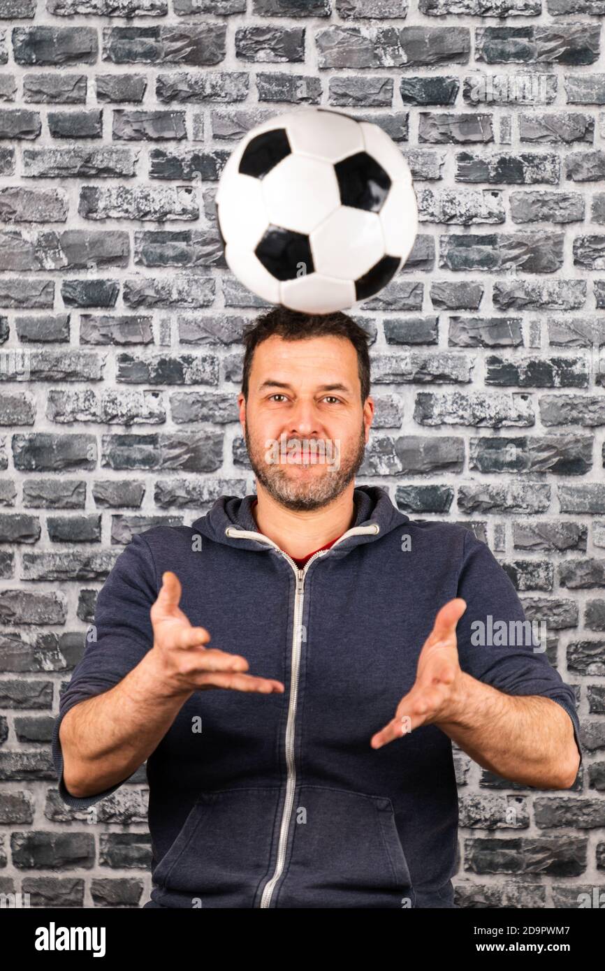 Vertical shot of a caucasian man playing with a soccer ball in front of ...