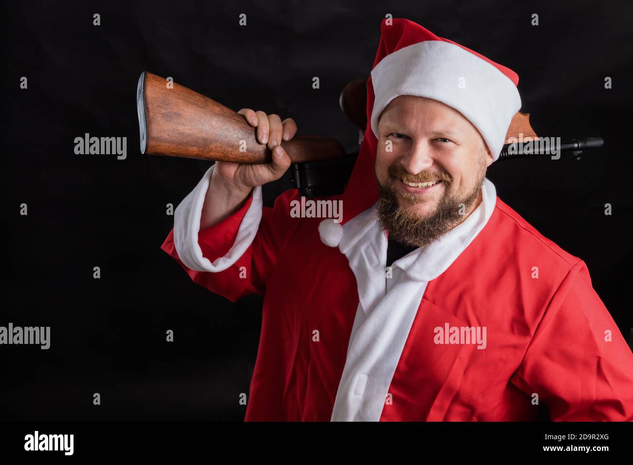 Cheerful Santa with machine gun studio portrait on black background ...