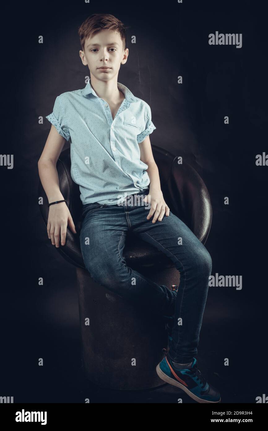 Young cheerful boy sitting on chair studio portrait Stock Photo - Alamy