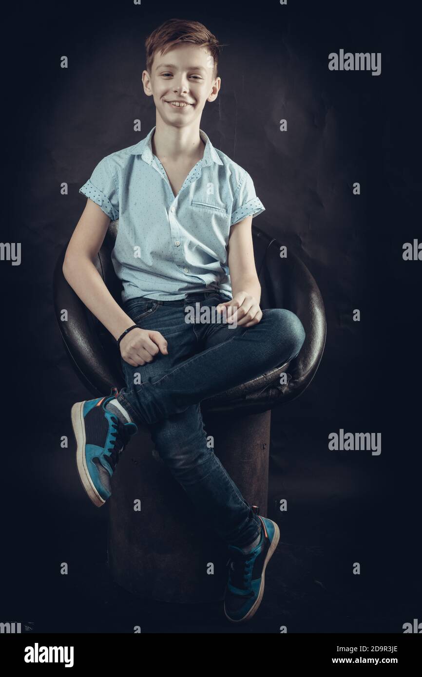 Young cheerful boy sitting on chair studio portrait Stock Photo - Alamy