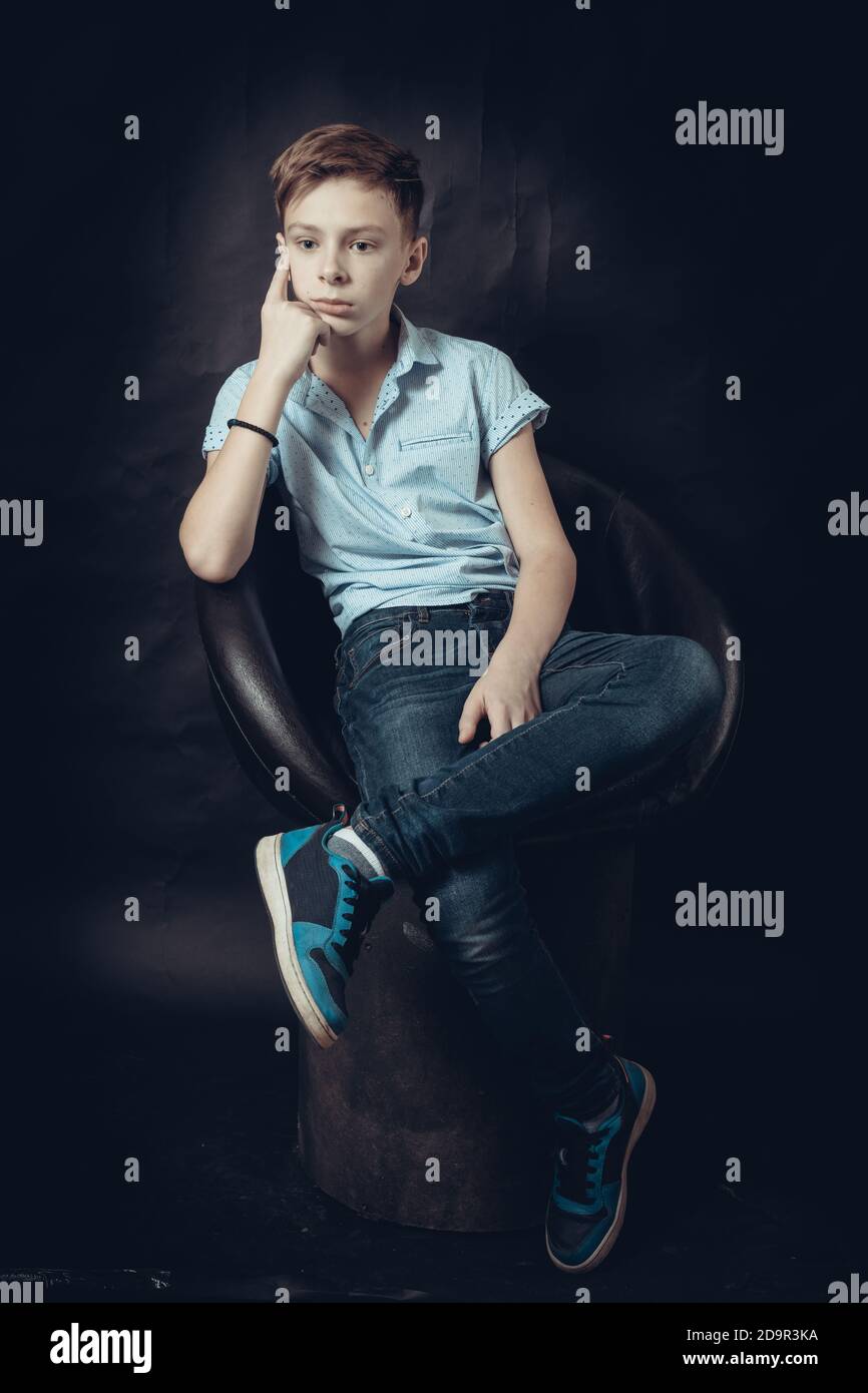 Young cheerful boy sitting on chair studio portrait Stock Photo - Alamy