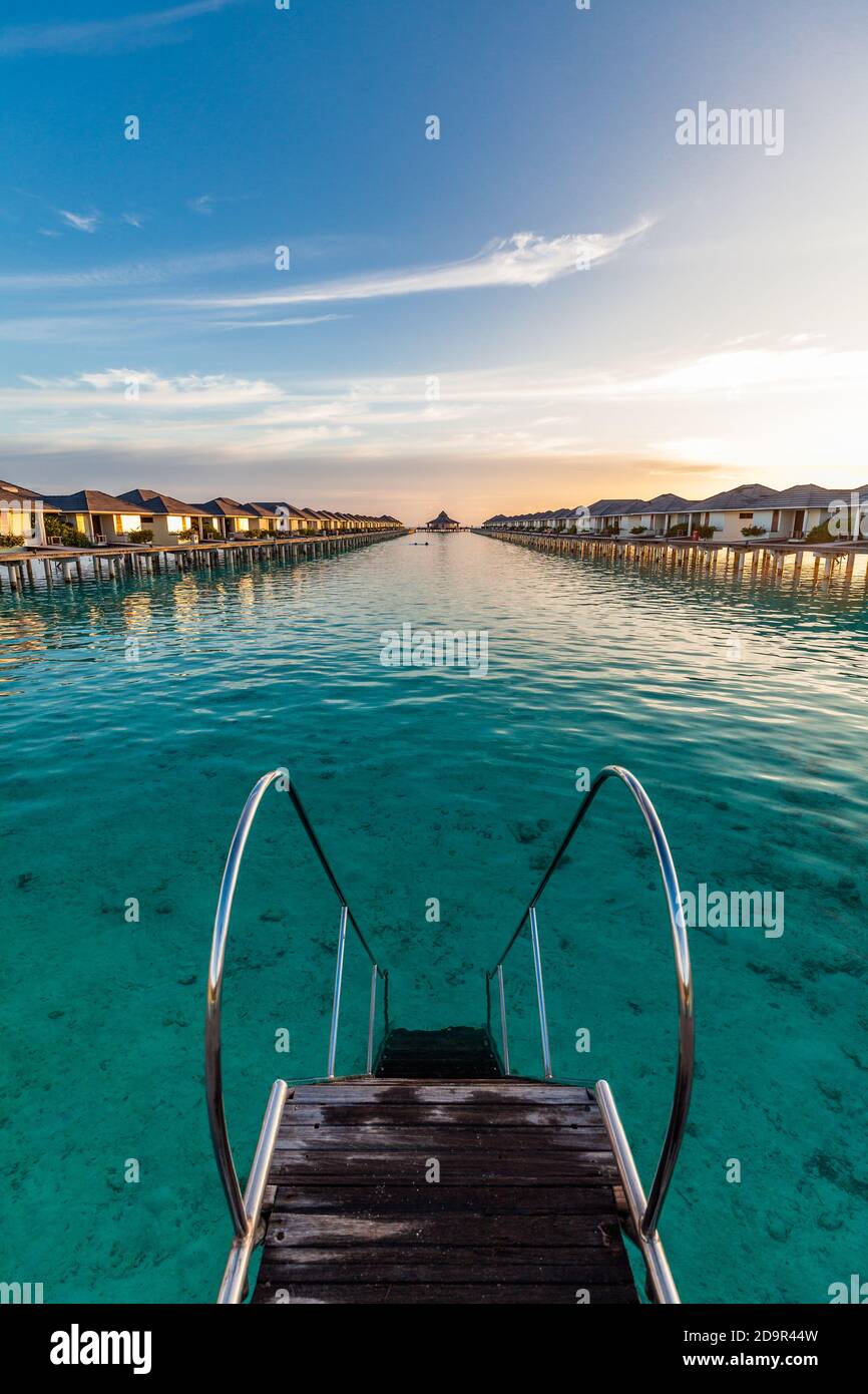 Jetty over swimming atoll and a tropical resort island in Maldives ...