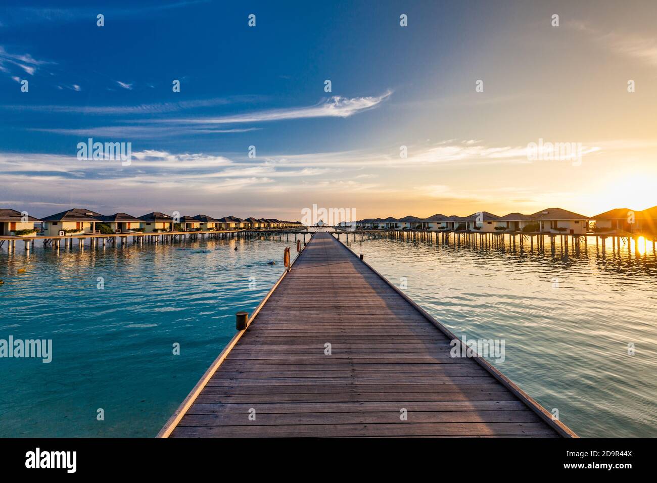 Jetty over swimming atoll and a tropical resort island in Maldives ...