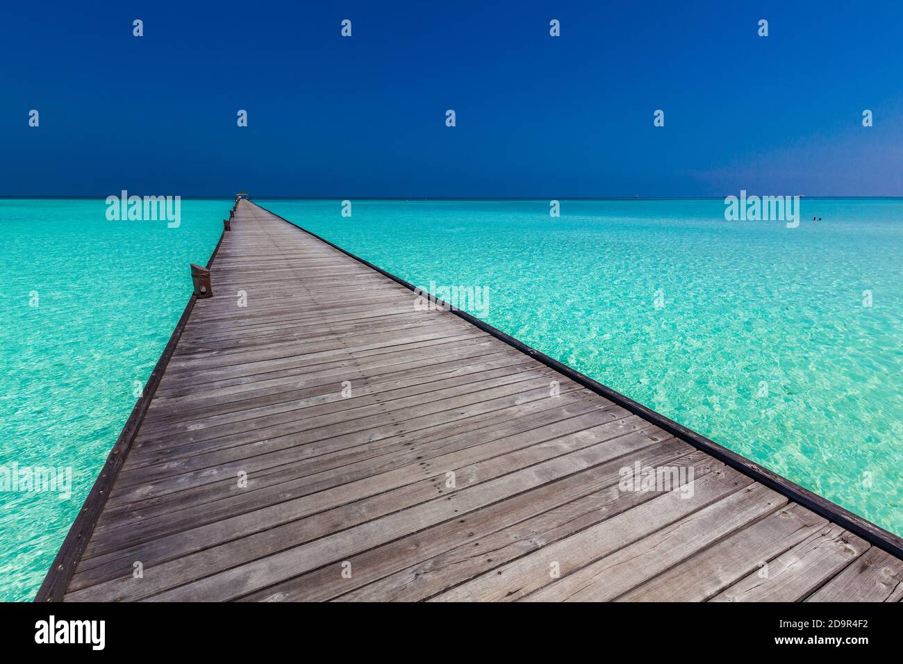 Jetty over swimming atoll and a tropical resort island in Maldives ...