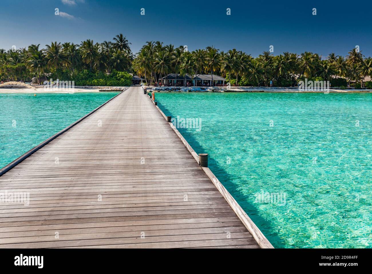 Jetty over swimming atoll and a tropical resort island in Maldives ...