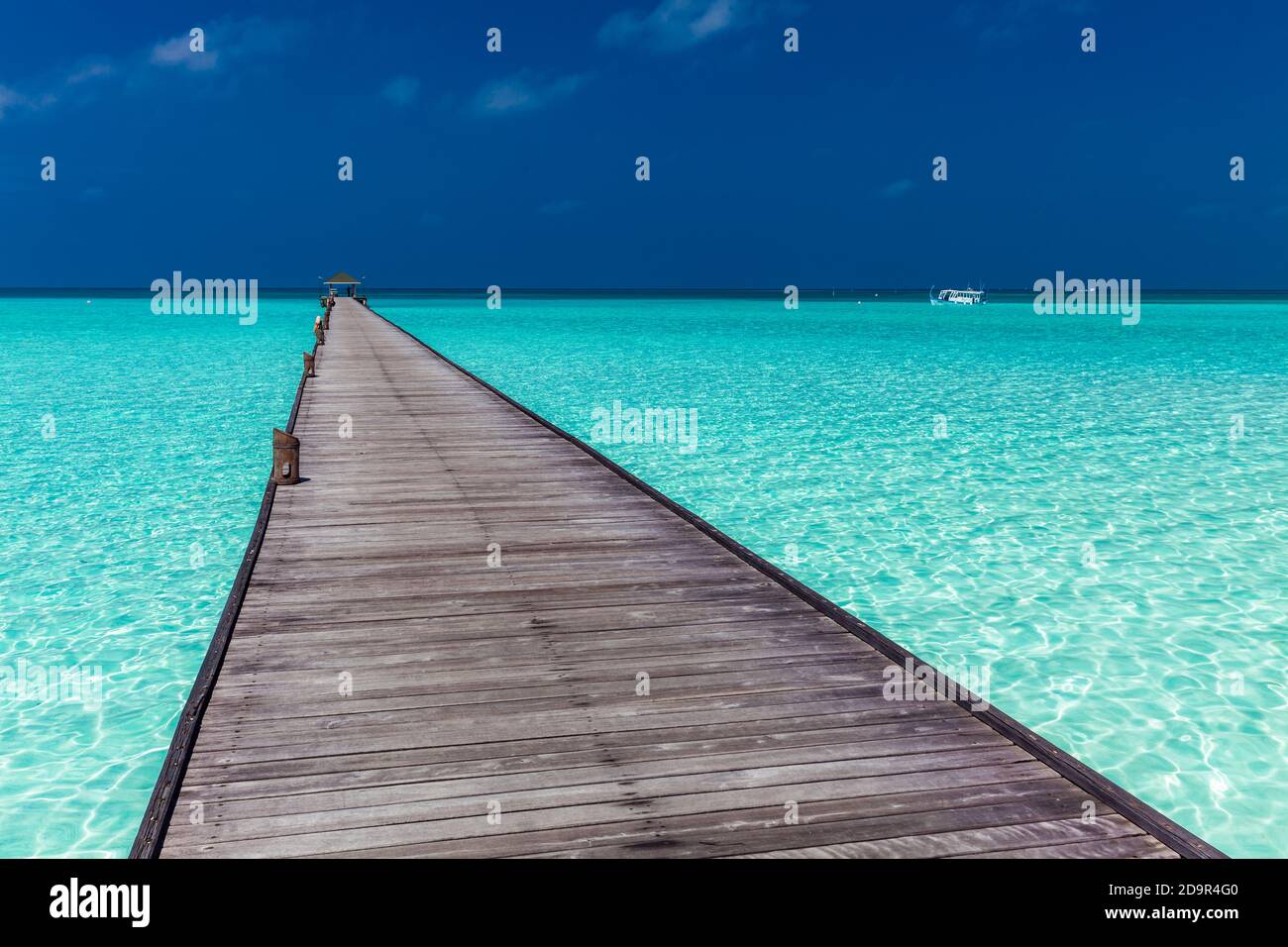 Jetty over swimming atoll and a tropical resort island in Maldives ...