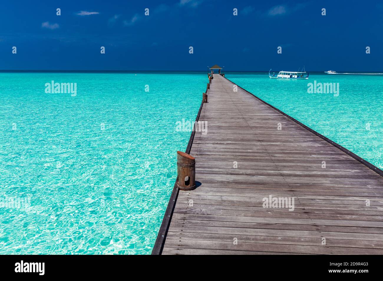 Jetty over swimming atoll and a tropical resort island in Maldives ...