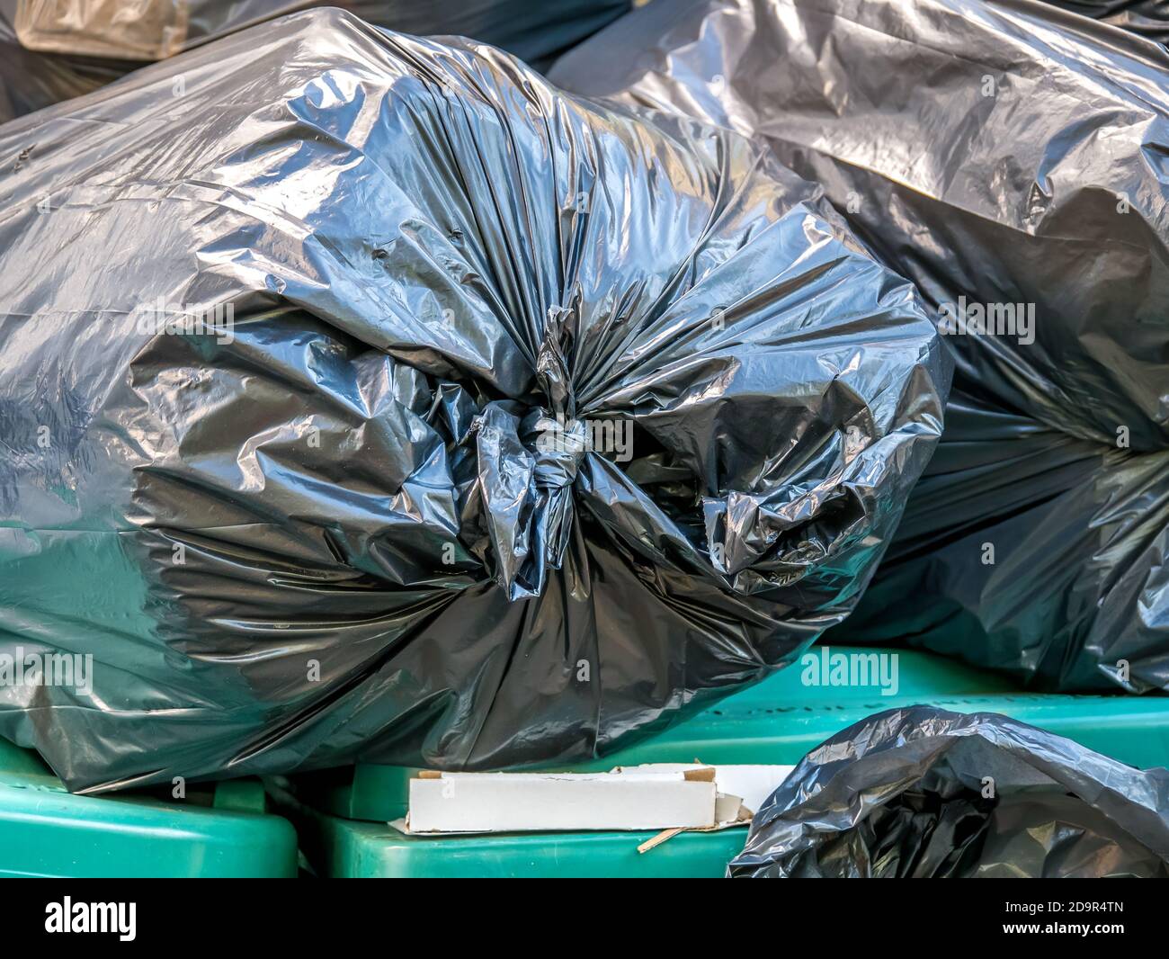 Plastic garbage bags on top of green garbage bins Stock Photo - Alamy