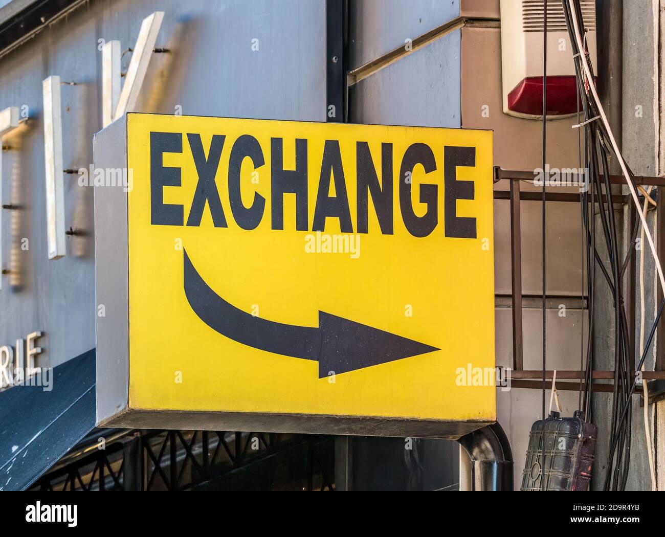 Yellow exchange sign board with a black arrow pointing in the direction ...