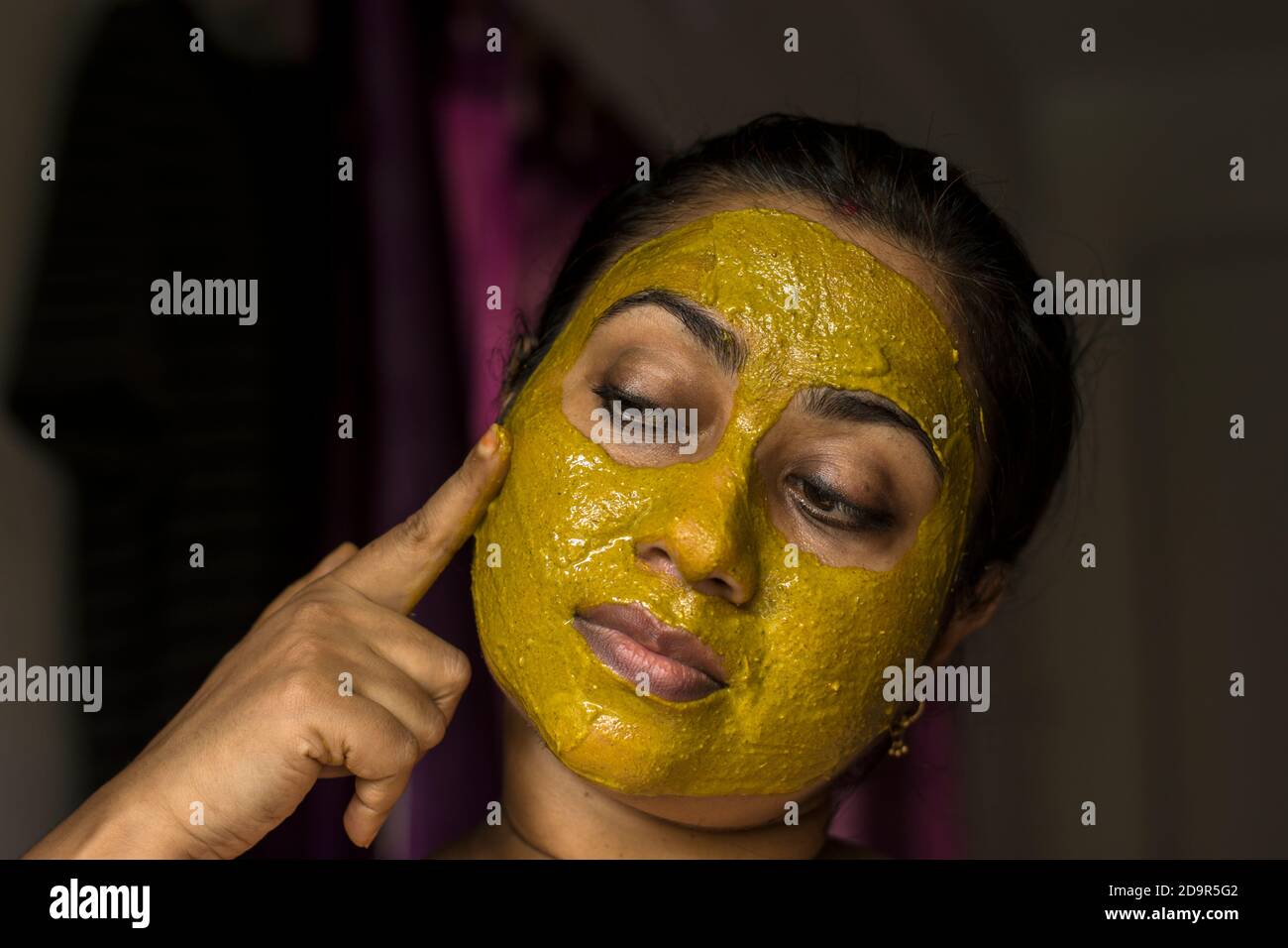 Close up of a beautiful woman with cosmetic facial green mask treatment ...