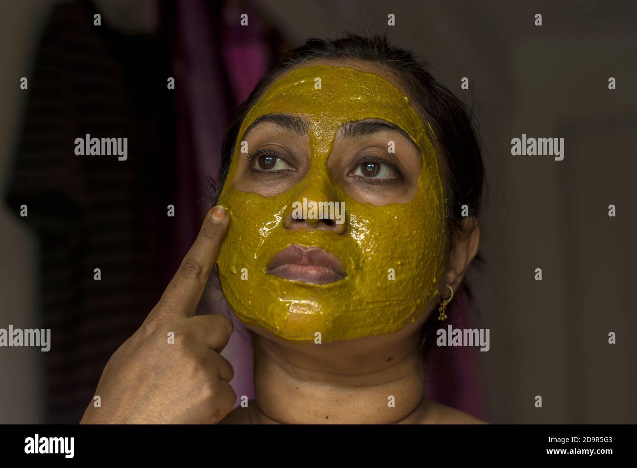 Close up of a beautiful woman with cosmetic facial green mask treatment ...