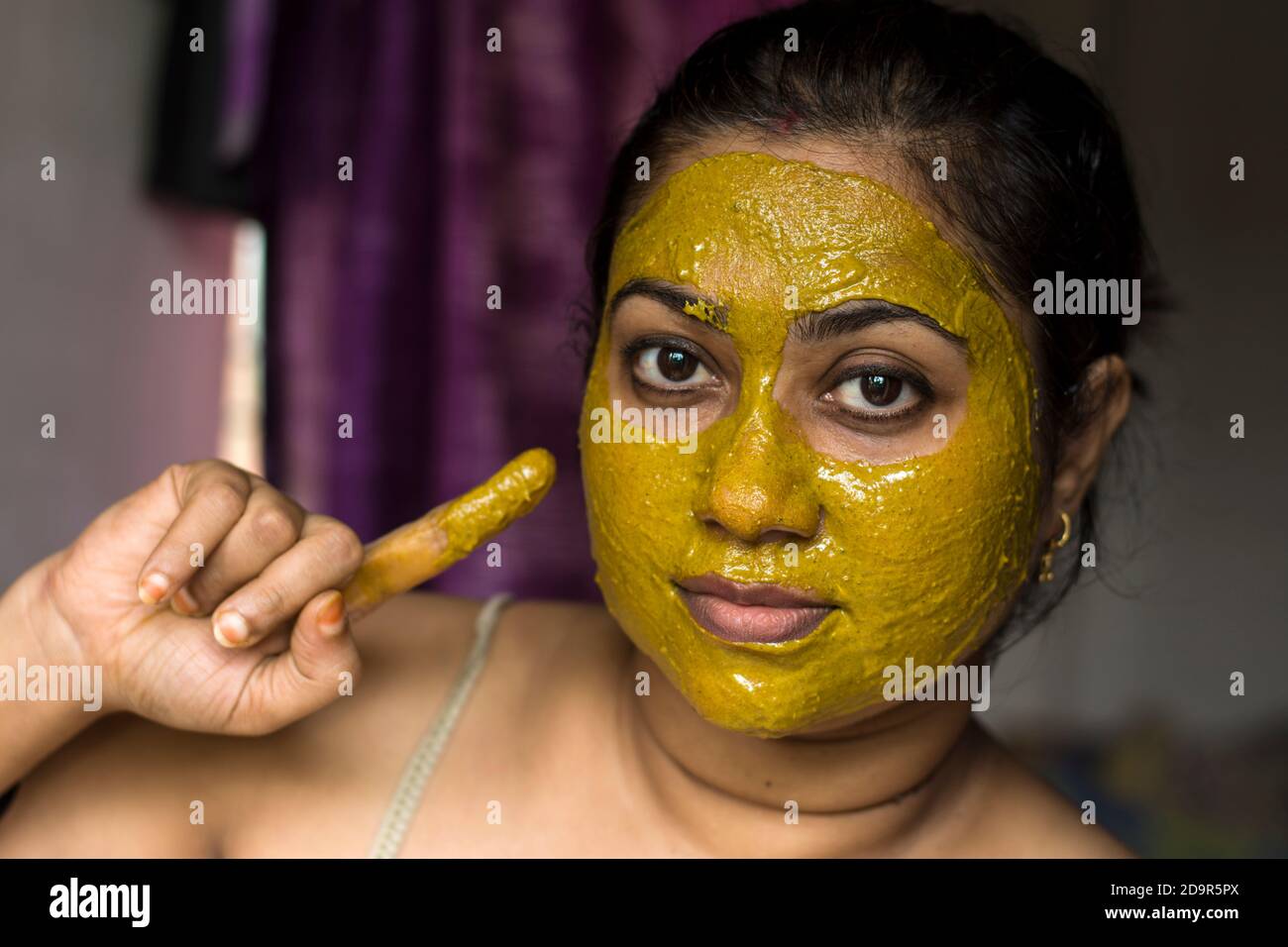 Close up of a beautiful woman with cosmetic facial green mask treatment ...