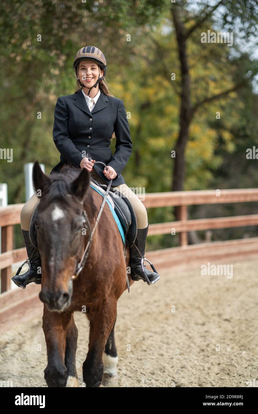 woman riding horse, english saddle, in arena surrounded by oak trees ...