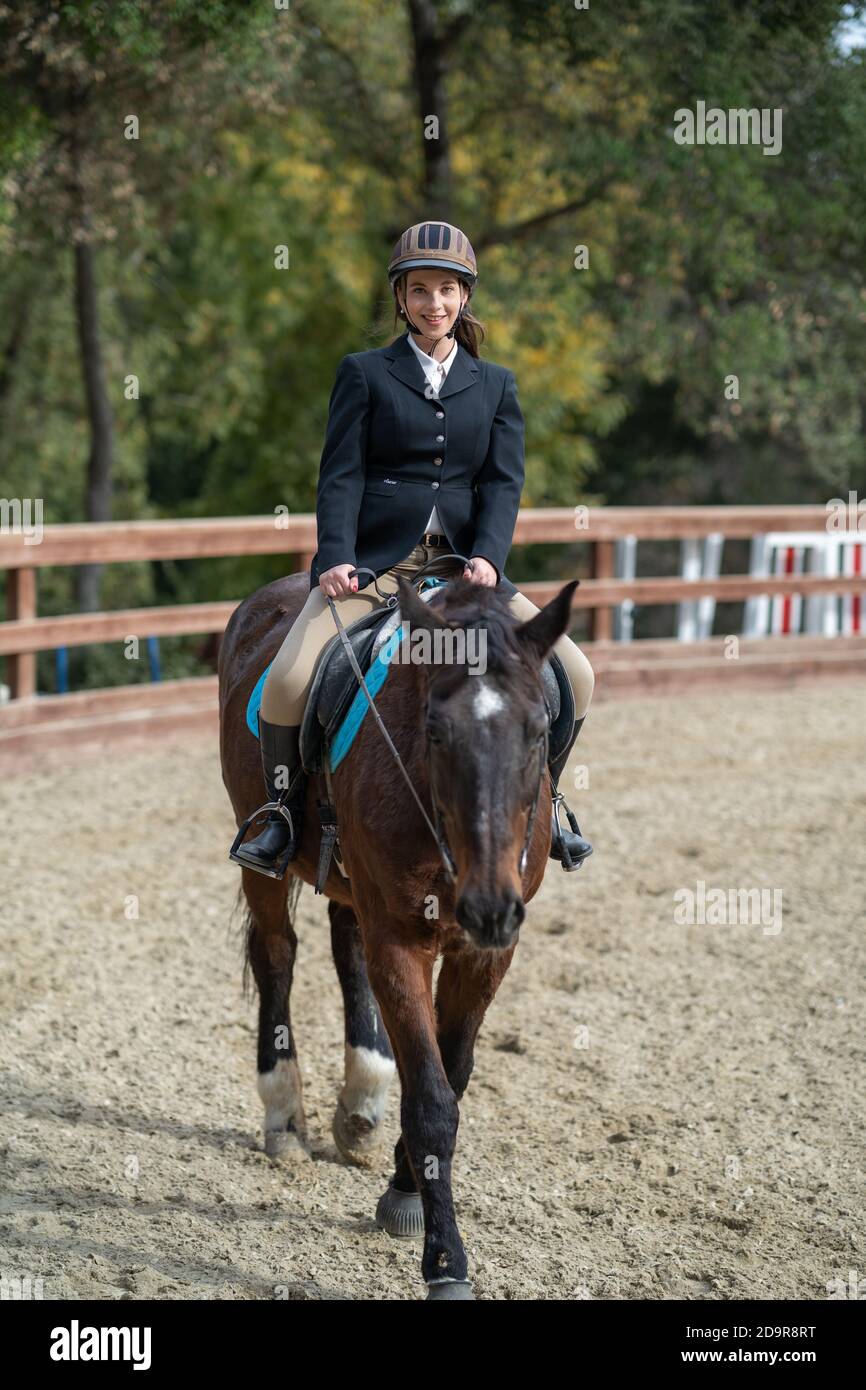 woman riding horse, english saddle, in arena surrounded by oak trees ...