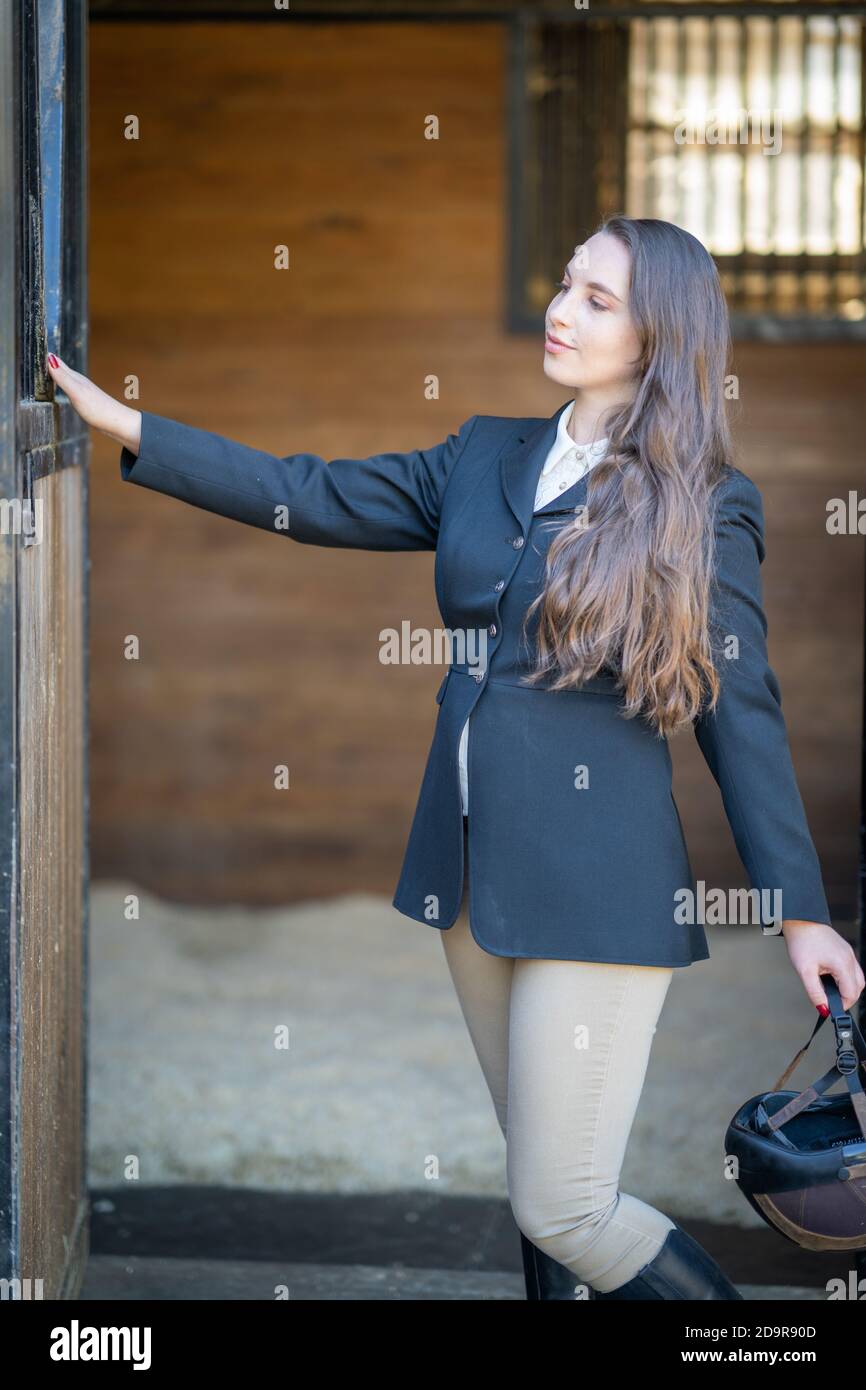 equestrian woman dressed in english riding standing outside stable door ...