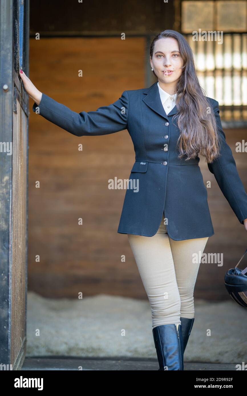 equestrian woman dressed in english riding standing outside stable door ...