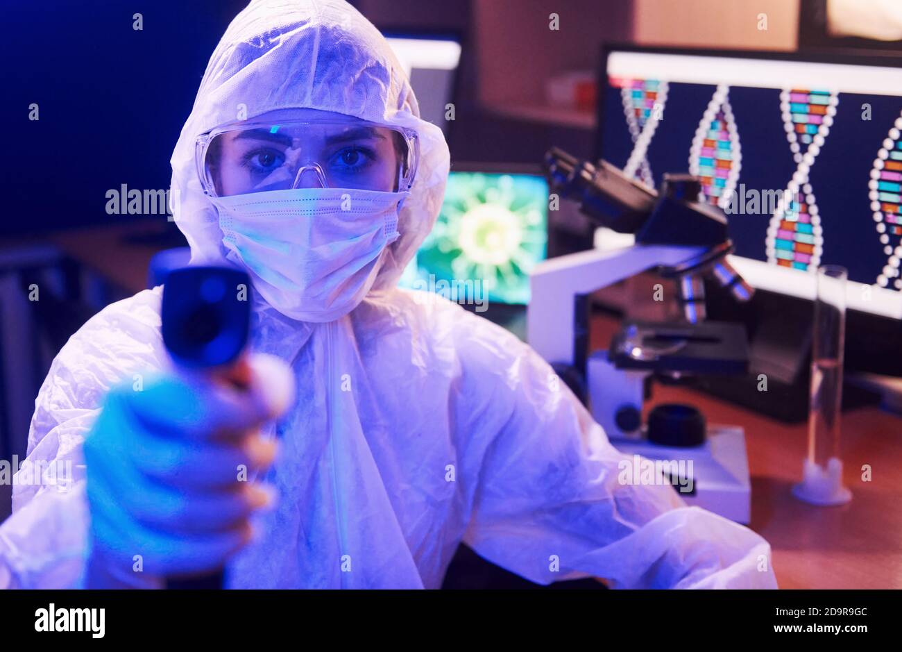 Nurse in mask and white uniform, holding infrared thermometer and ...