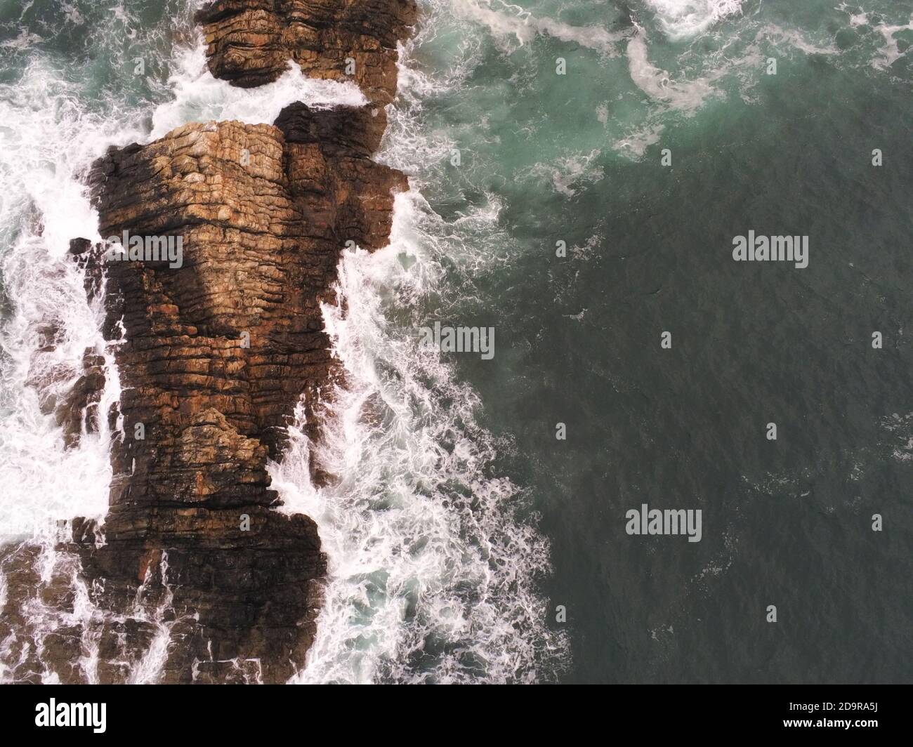 Aerial top view of cliffs surrounded by wavy waters - perfect for ...