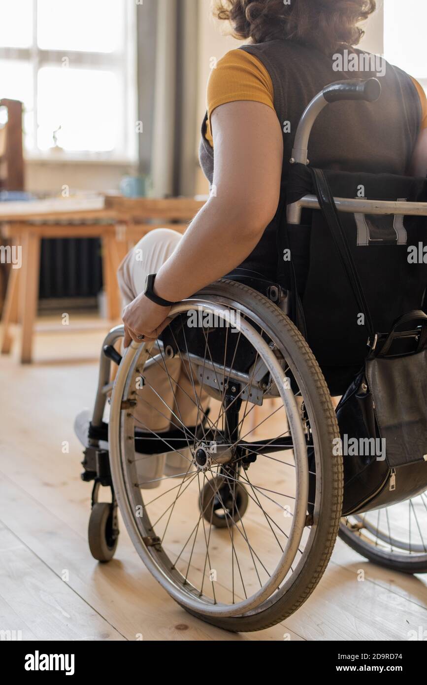 Back view of young disable female sitting in wheelchair in front of ...