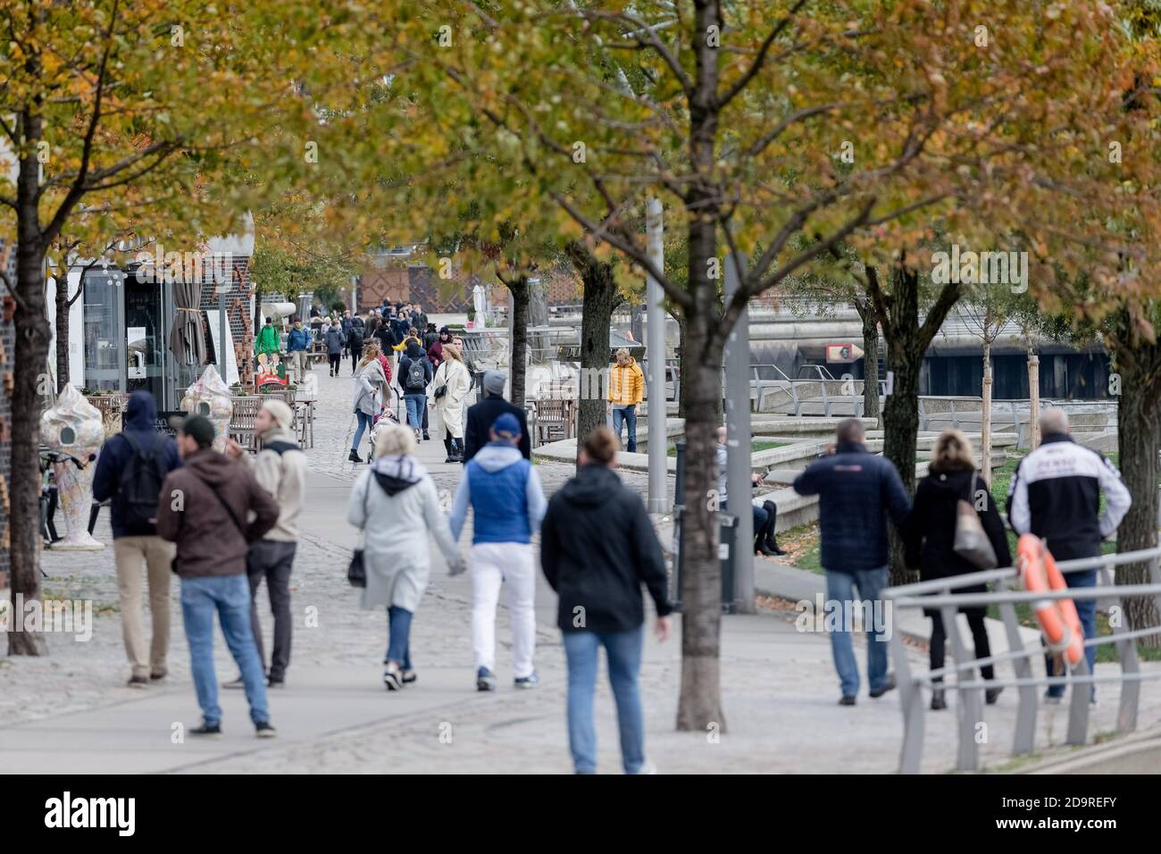 24 October 2020, Hamburg: Passers-by walk under autumnally colored ...