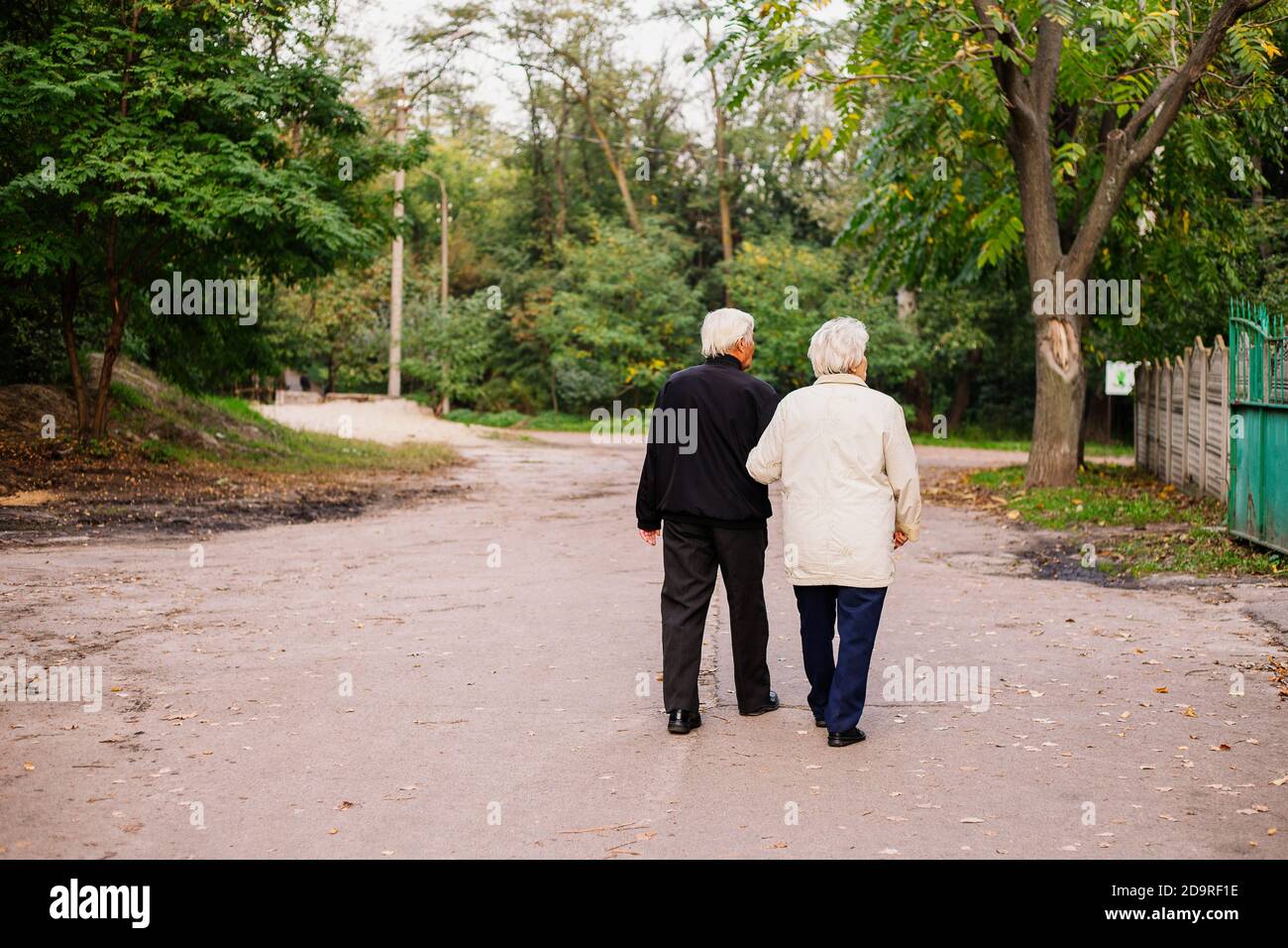 A picture of an old couple strolling in the park. Picture from the back ...