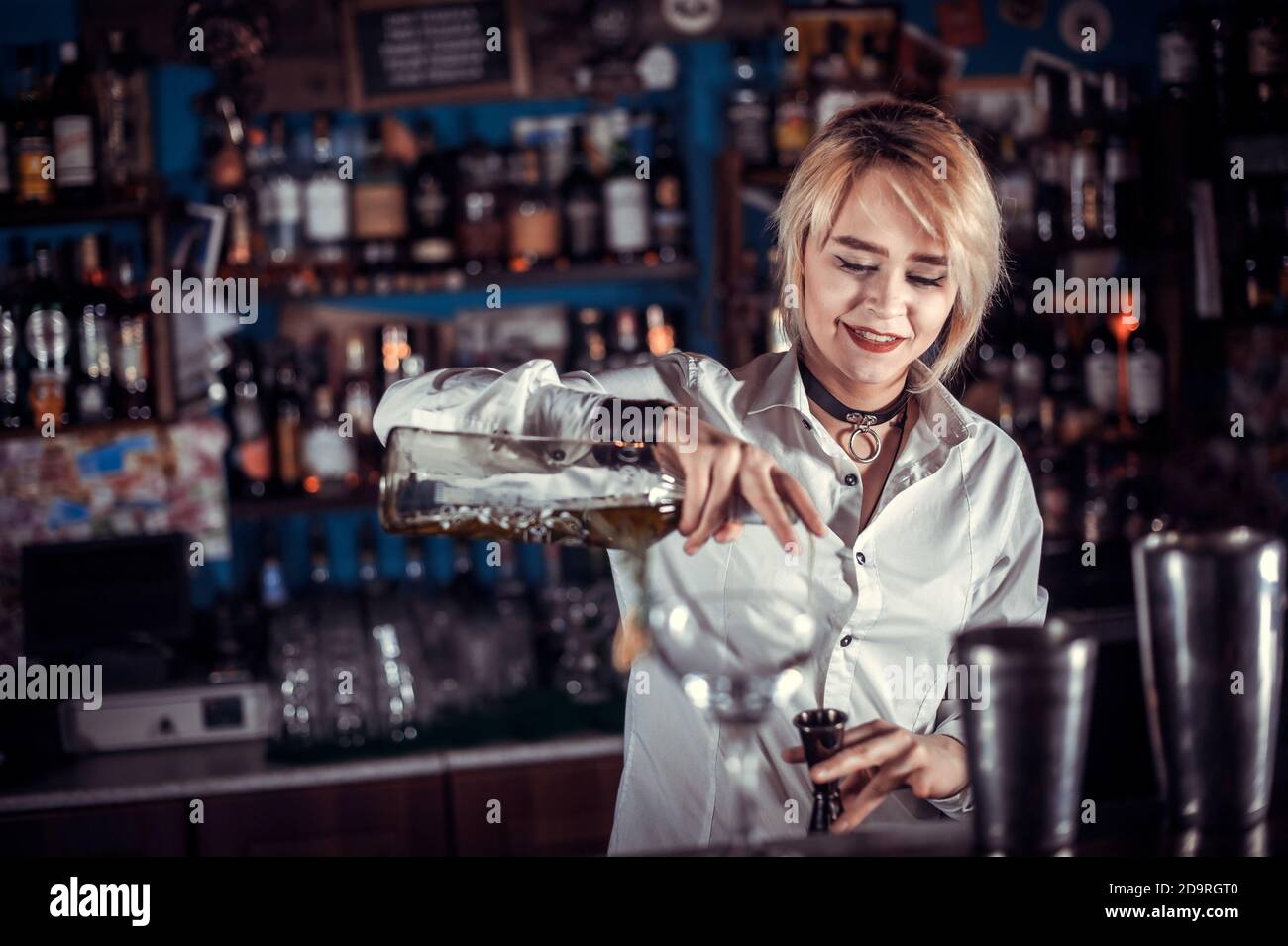 Charming woman bartending formulates a cocktail while standing near the ...