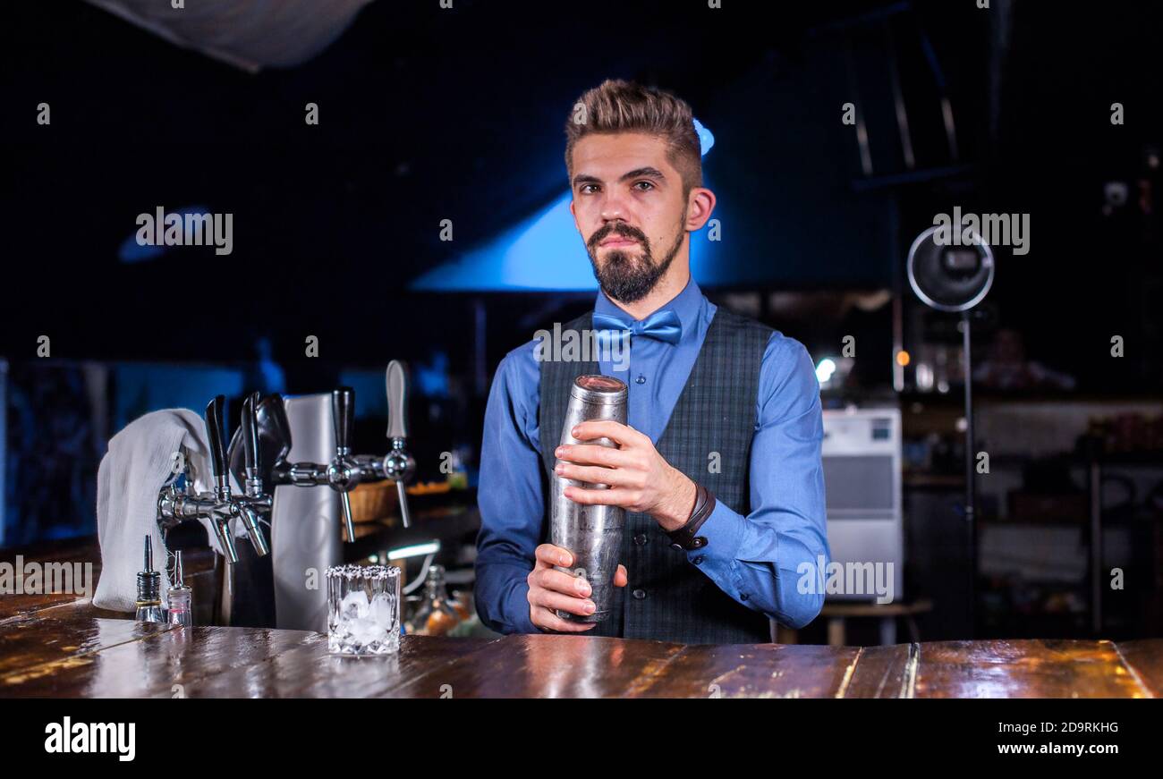 Experienced barman demonstrates the process of making a cocktail while ...