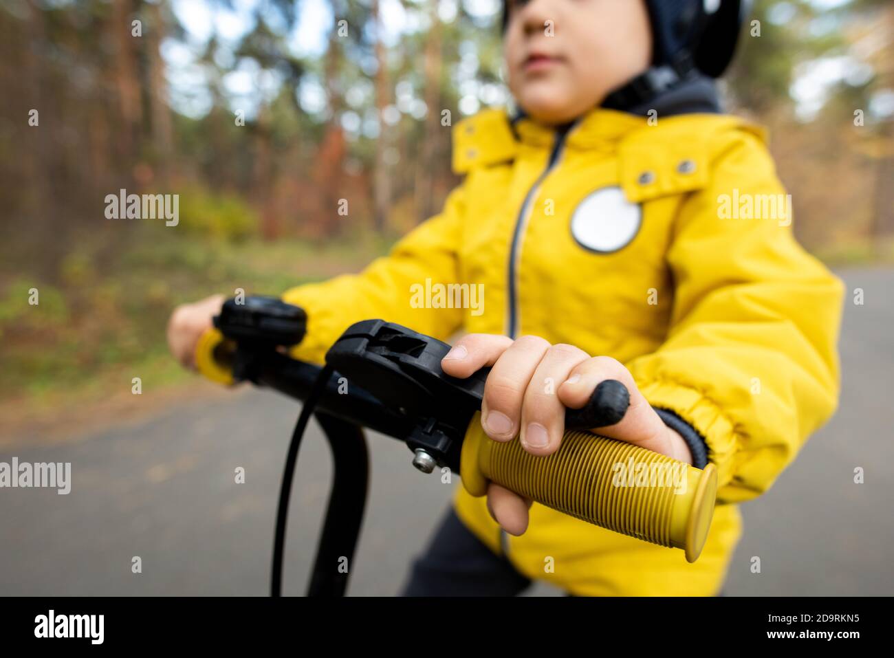 Hand of active little boy holding by handles while riding his balance ...