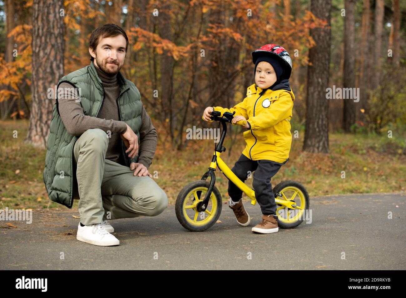 Happy young father squatting by his adorable little son sitting on ...
