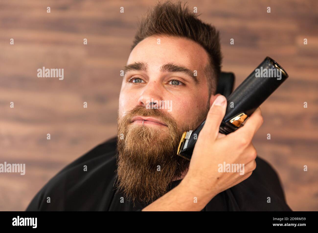 View from above of a customer in a barber shop, his beard is being ...