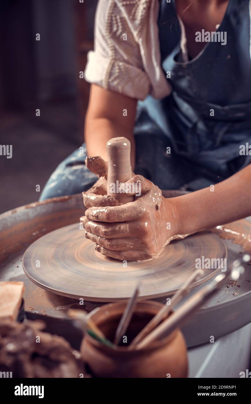 Professional potter is working on pottery wheel. Craft manufacture ...