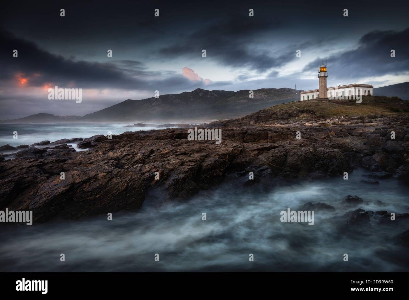 A beautiful lighthouse on a hill with its light on at sunset Stock ...