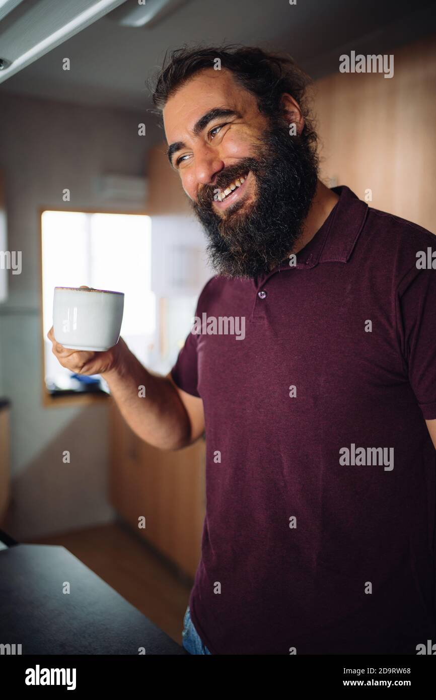 A bearded man smiles with his arm raised holding a cup of coffee Stock ...