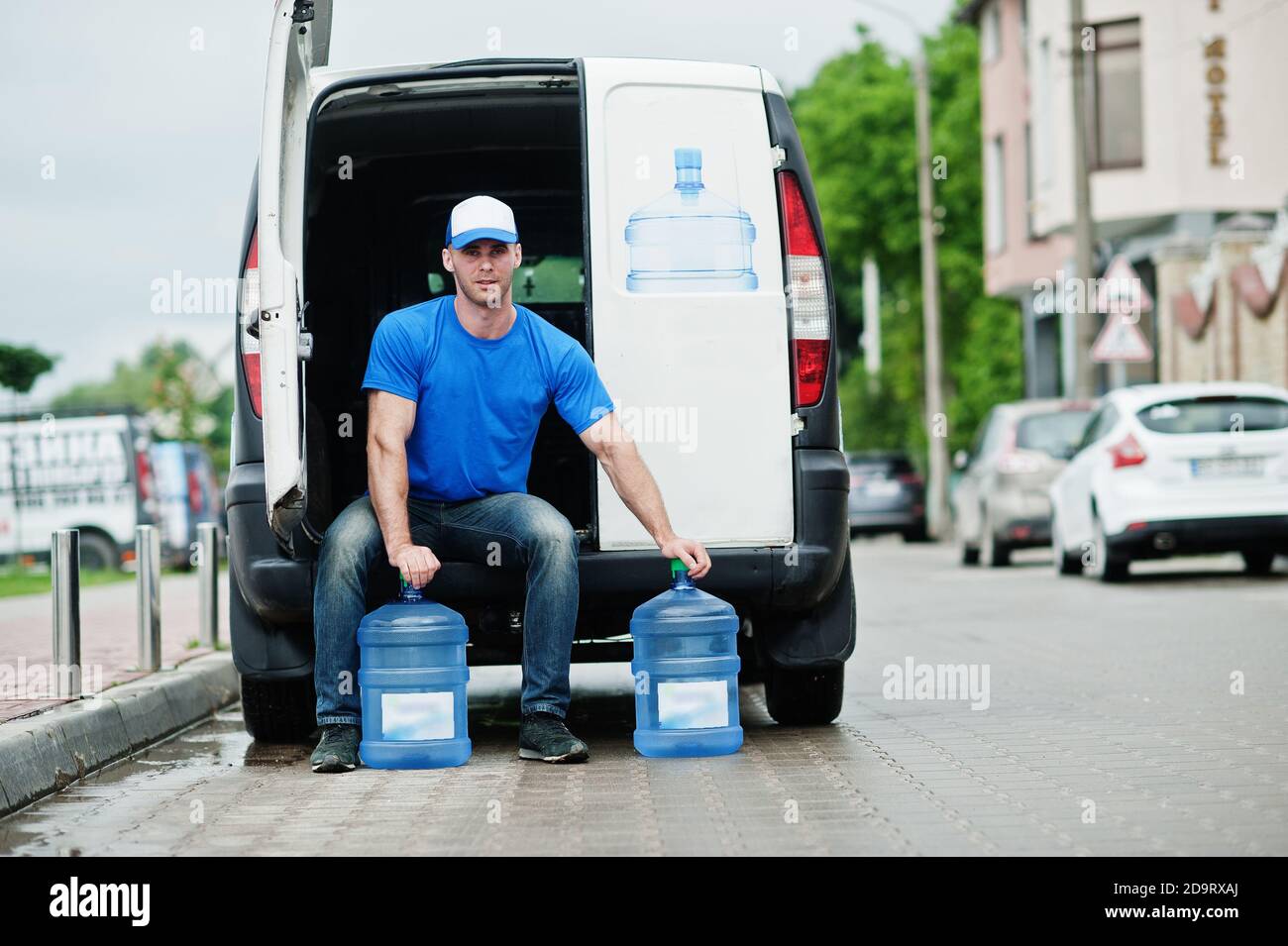 Delivery man in front cargo van delivering bottles of water Stock Photo ...