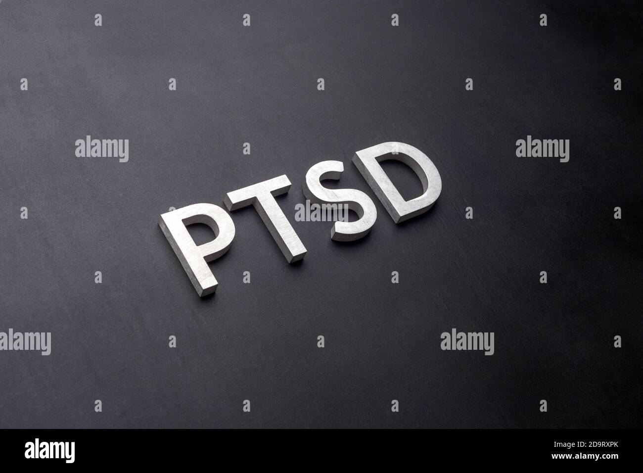 the word PTSD laid with silver metal letters on flat black background ...