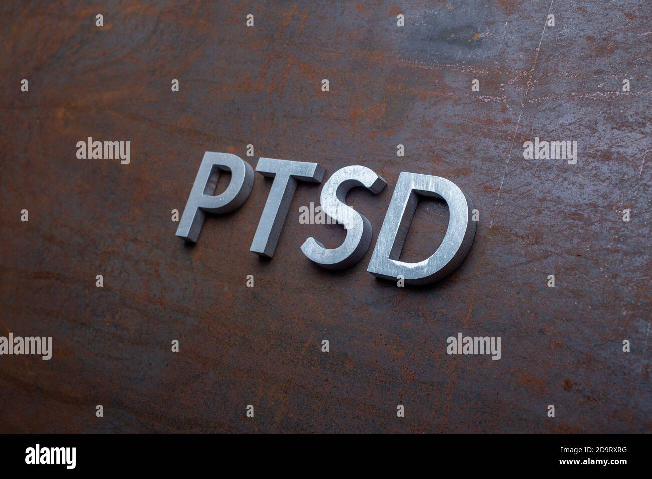 the word PTSD laid with silver metal letters on flat rusted steel sheet ...