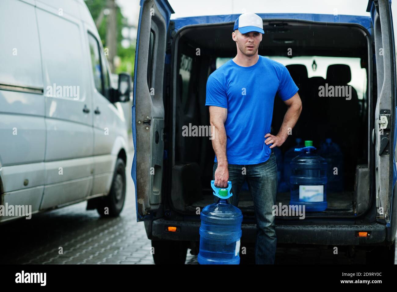 Delivery man in front cargo van delivering bottles of water Stock Photo ...