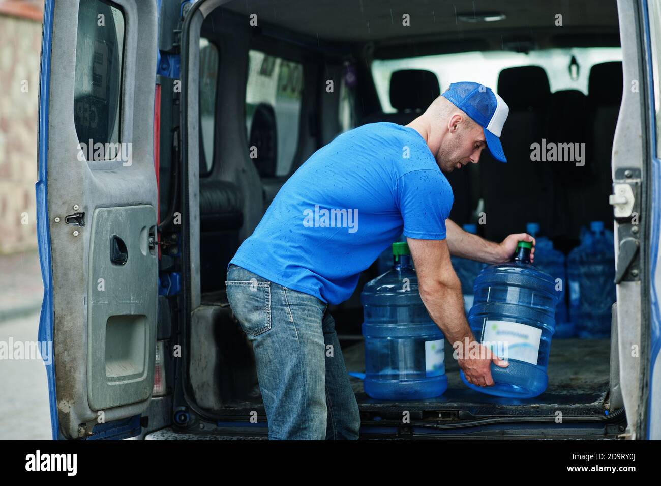 Delivery man in front cargo van delivering bottles of water Stock Photo ...