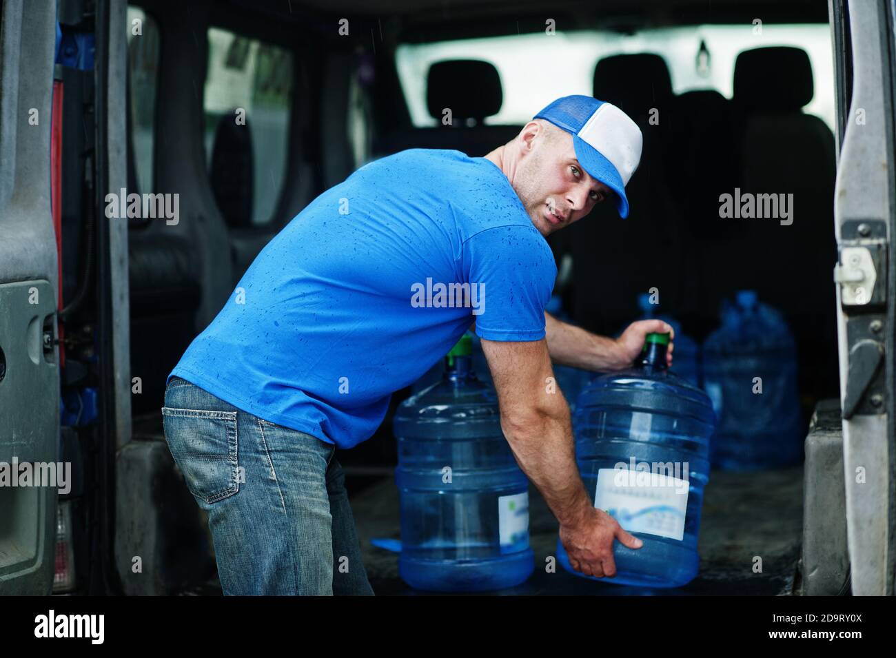 Delivery man in front cargo van delivering bottles of water Stock Photo ...
