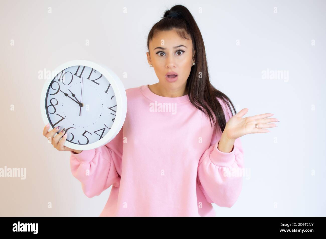 Surprised woman holding Big Clock, isolated on white background ...