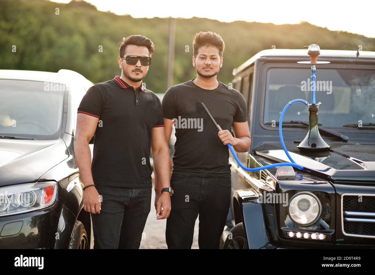 Two asian brothers man wear on all black posed near suv cars and smoke ...