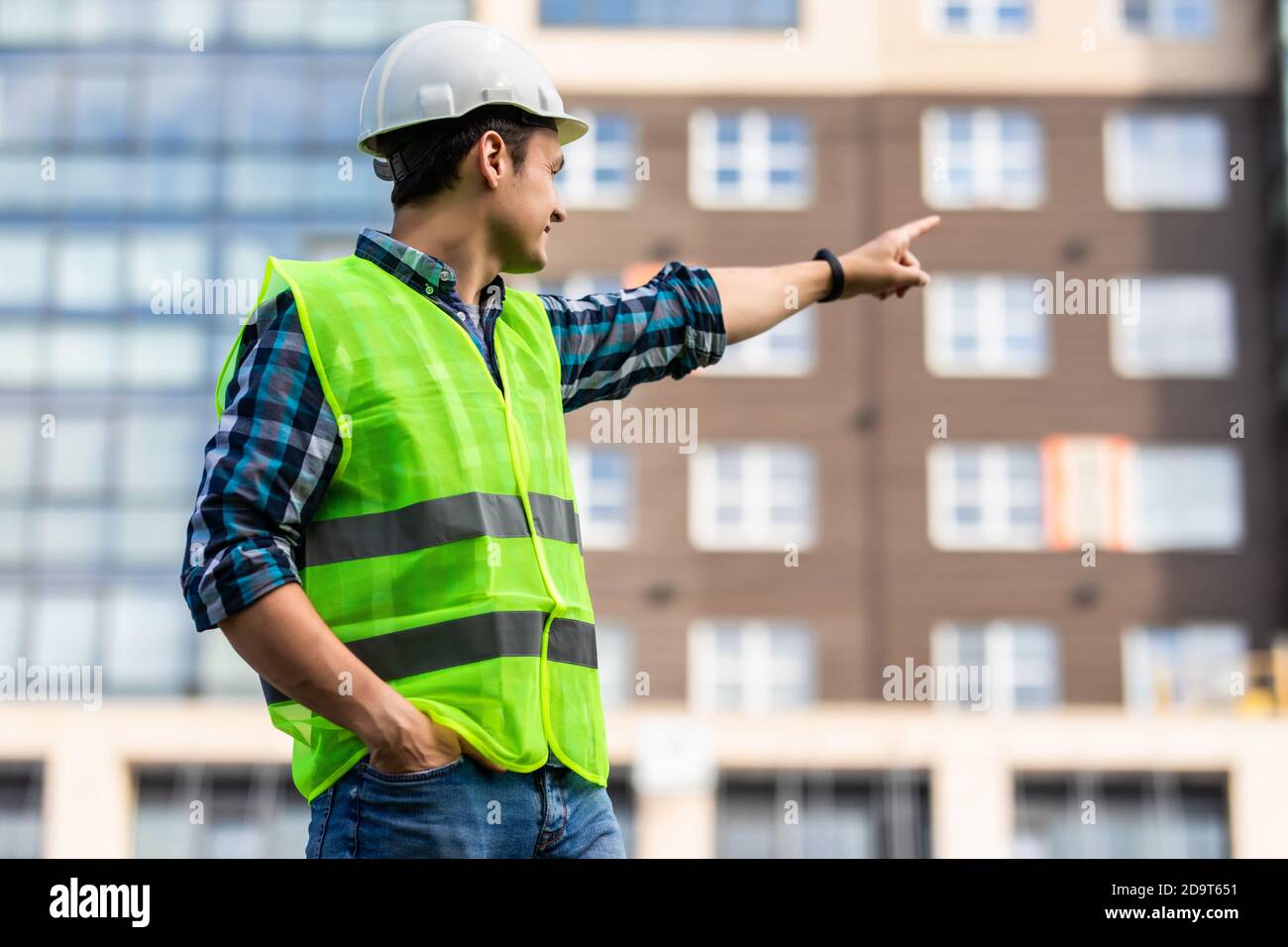 Builder pointed side on at construction site Stock Photo - Alamy