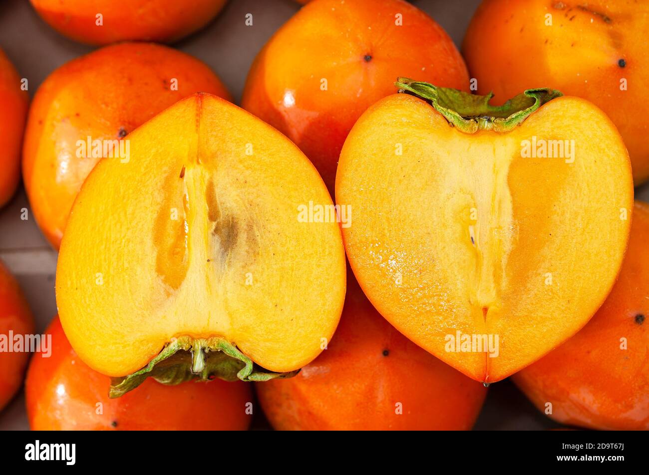 Fresh juicy ripe organic persimmons in a wooden box with cut in half ...