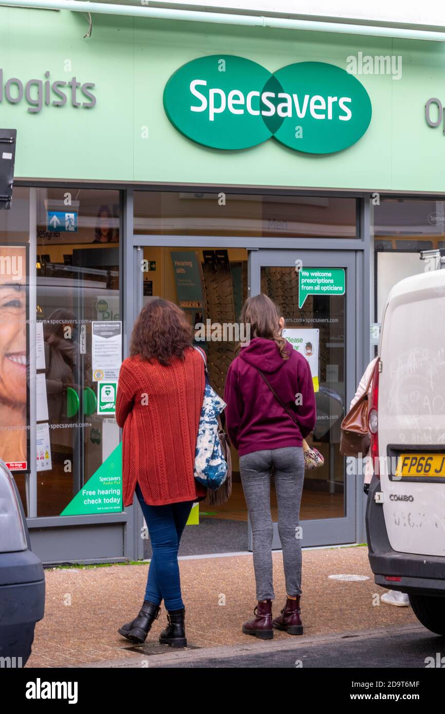 two people waiting outside of an opticians store during the covid 19 ...