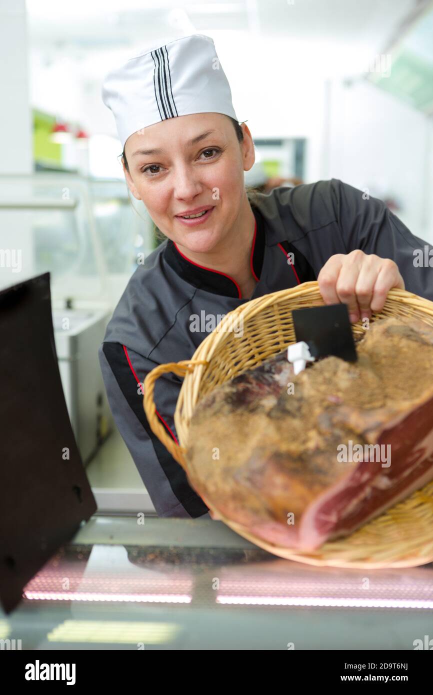 female butcher showing dried ham in basket Stock Photo - Alamy