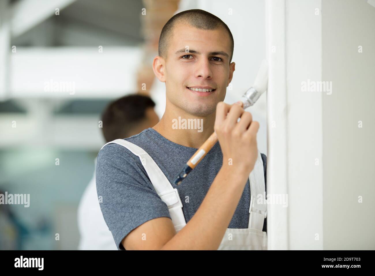 young commercial painter painting wall edge Stock Photo - Alamy