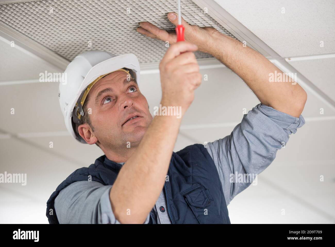 builder opening ceiling grill with a screwdriver Stock Photo - Alamy