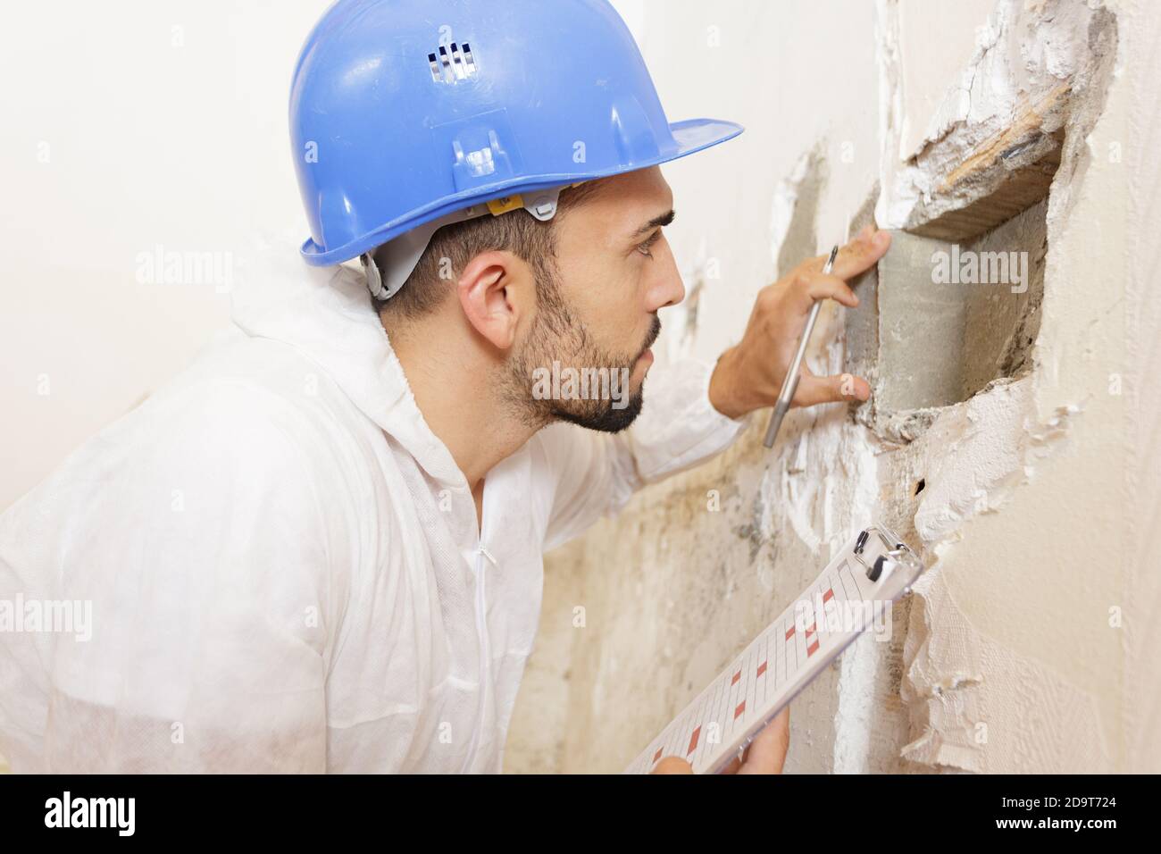 male builder inspecting recess in wall Stock Photo - Alamy