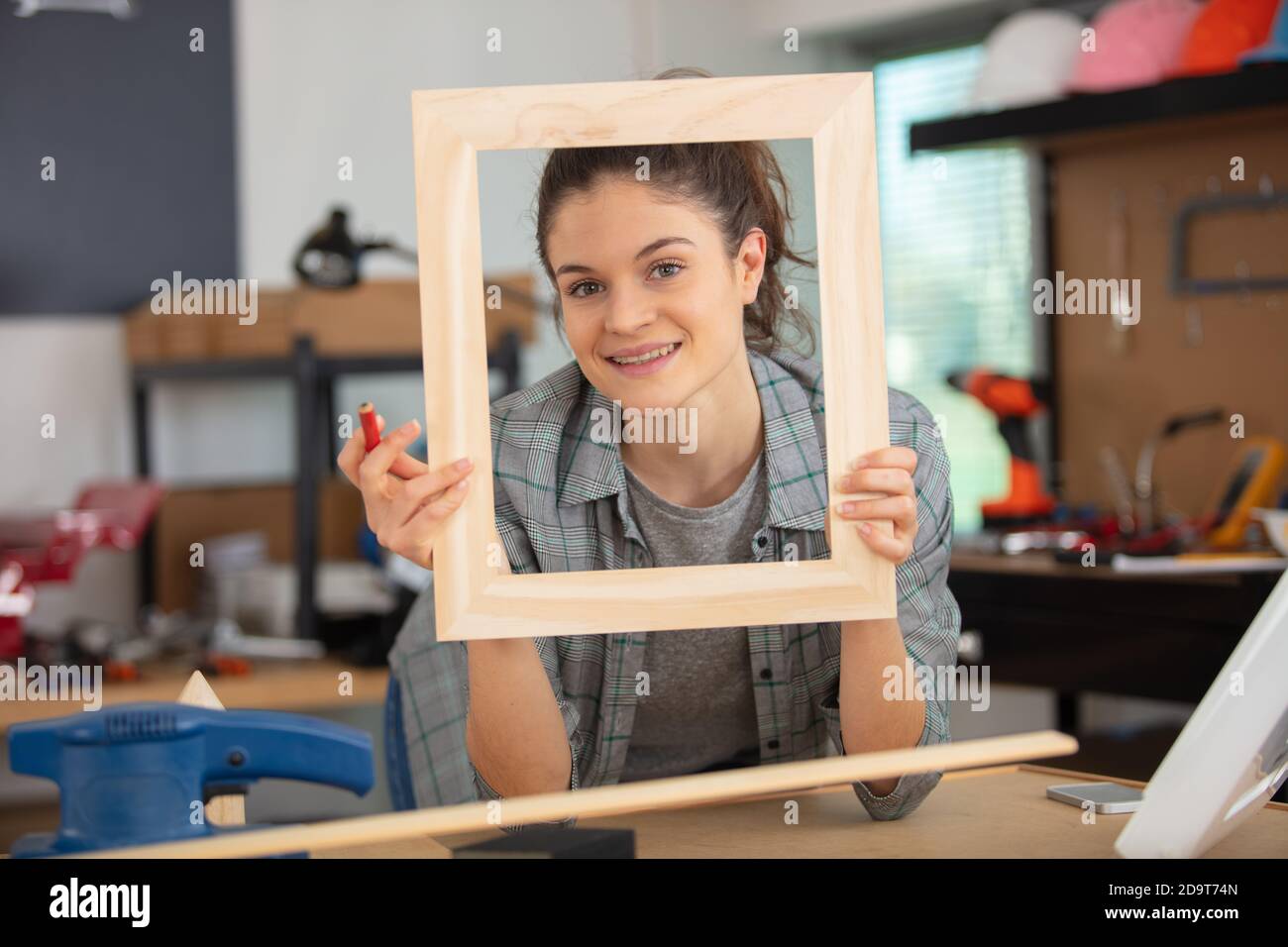 happy creative female carpenter holding wooden frame Stock Photo - Alamy