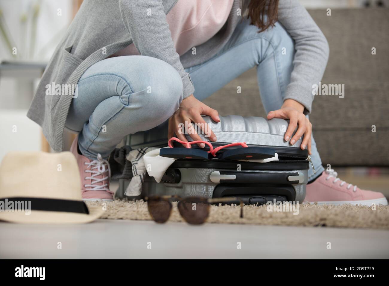 woman squashing her suitcase to close it Stock Photo - Alamy